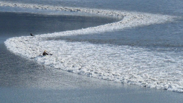 Kayakers ride tidal bore wave as it surges into Alaska's Turnagain Arm