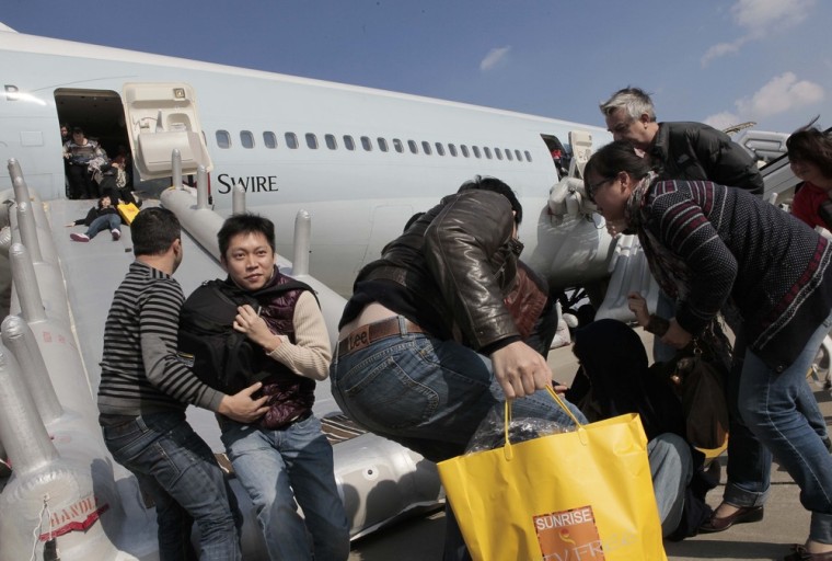 Passengers hang on to their luggage as they evacuate plane due to smoke ...