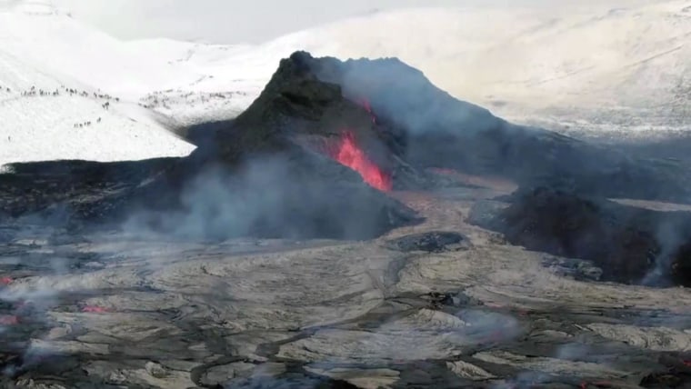 Volcano in Iceland is seen erupting as volleyball players continue game