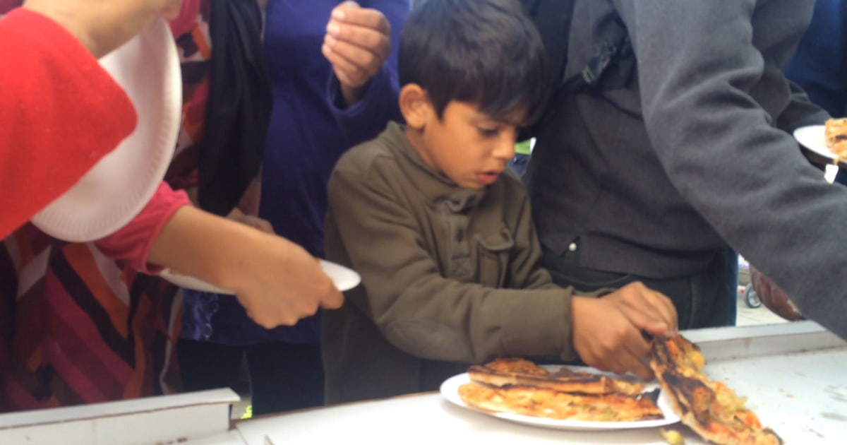 Hungry Syrian Migrants Line Up for Pizza