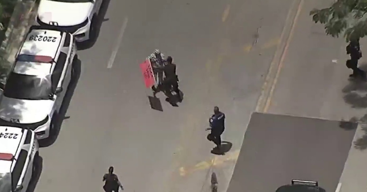 Anti-Trump protester wearing prisoner costume approaches Trump motorcade