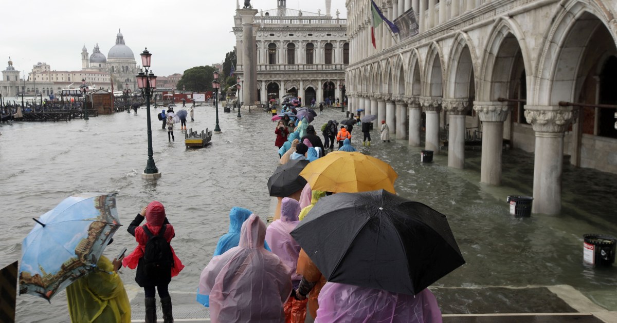 Tourists and residents slosh through a flooded Venice