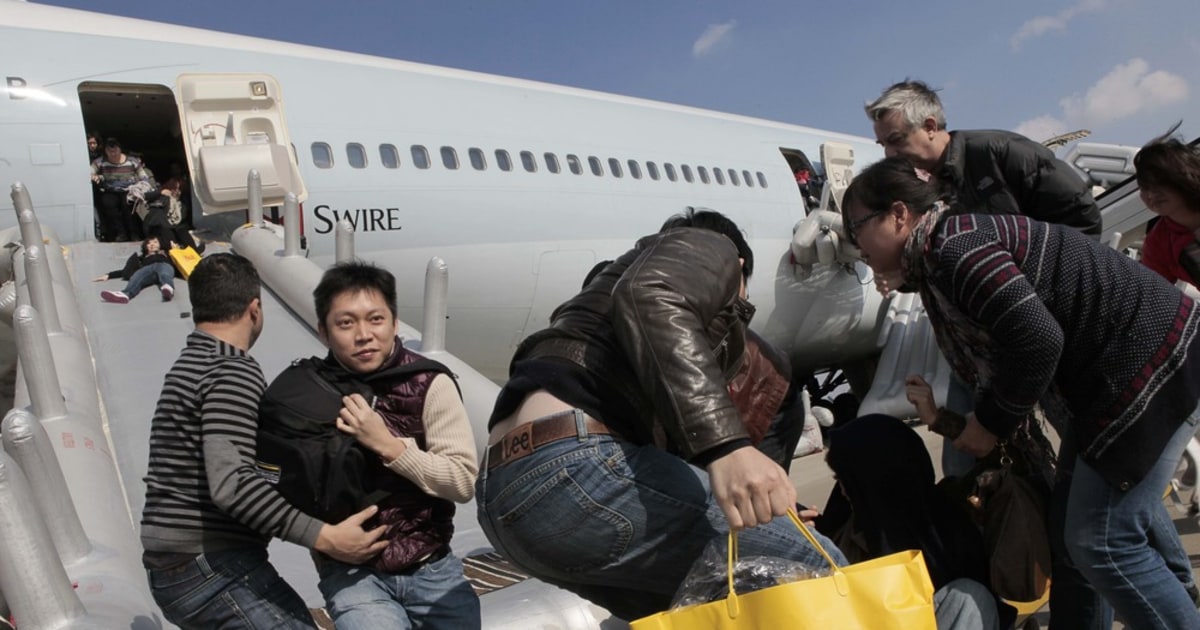 Passengers hang on to their luggage as they evacuate plane due to smoke ...