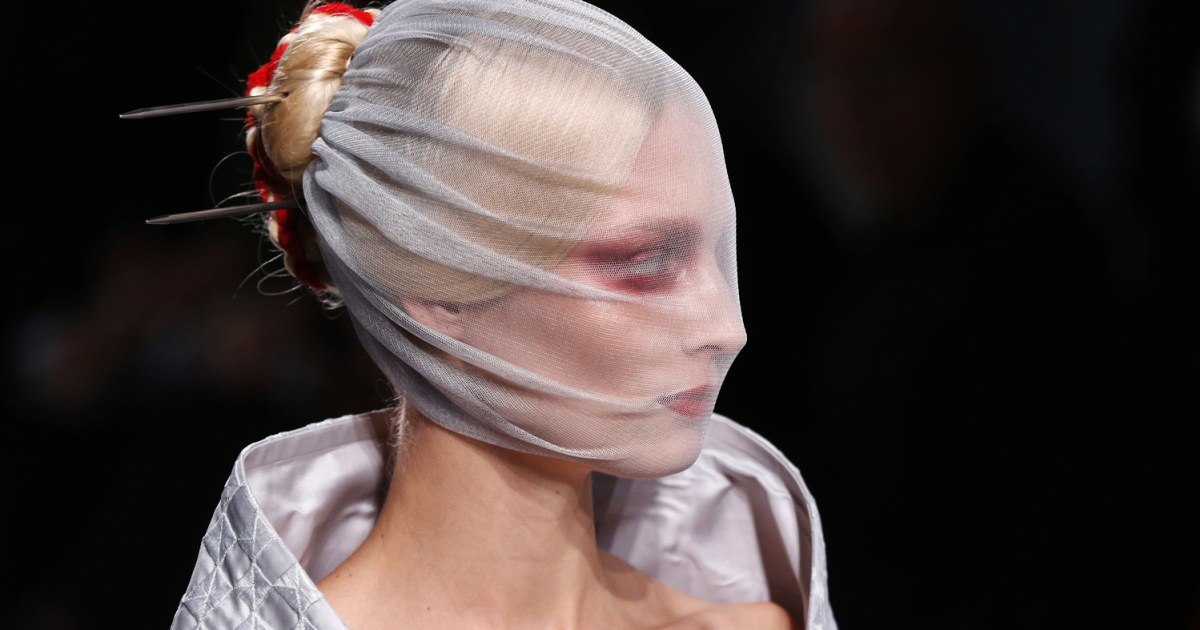 A veiled face of fashion walks down a Paris runway