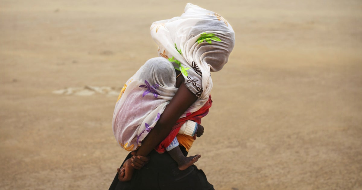 Mother and child make their way through sandstorm in Timbuktu