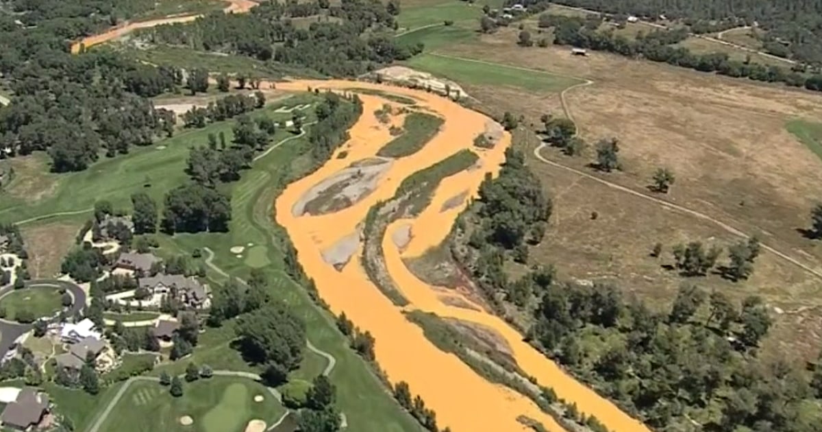 Orange sludge flows into river