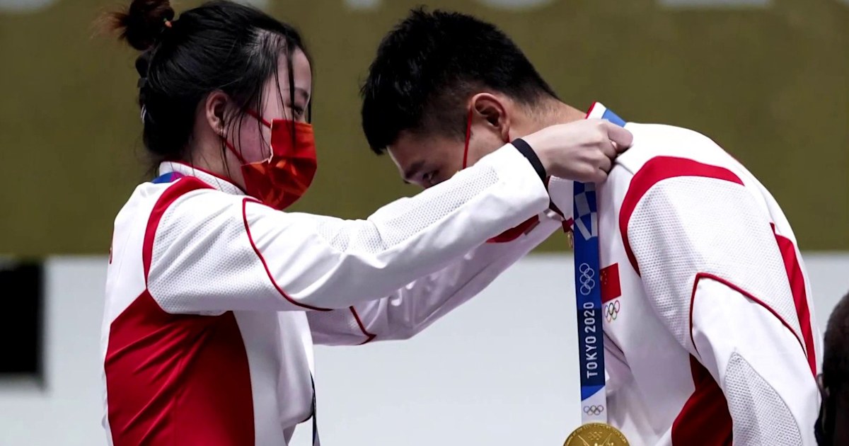 Olympic athletes help each other don their medals