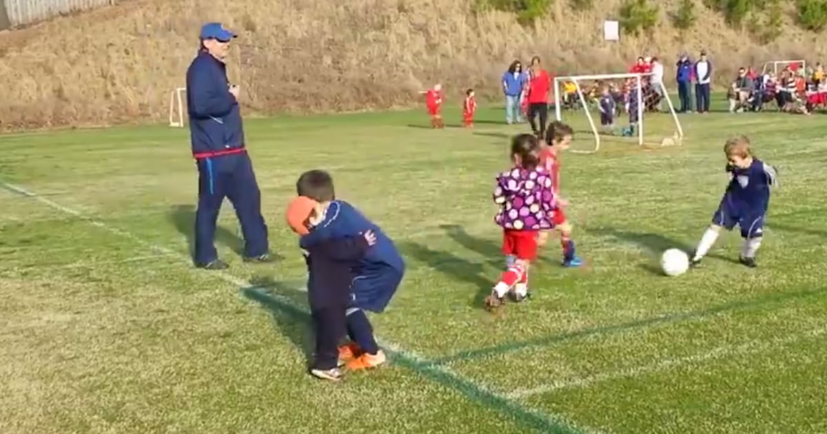 Little boy stops playing soccer to give brother an unofficial hug