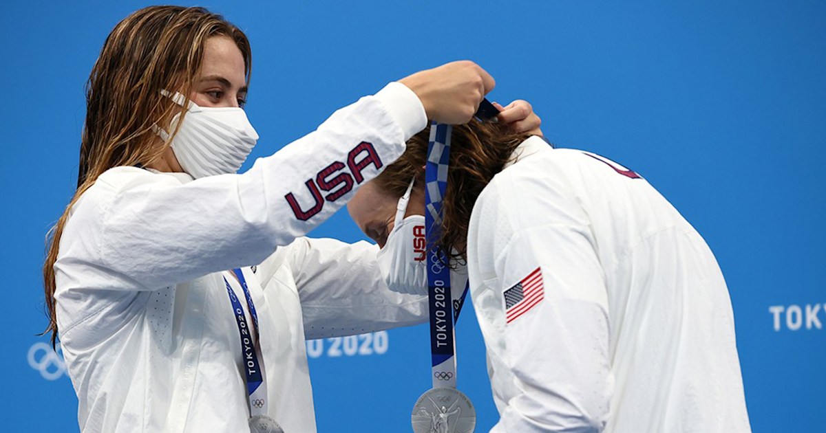 Olympians are showing true teamwork by placing medals around each other ...
